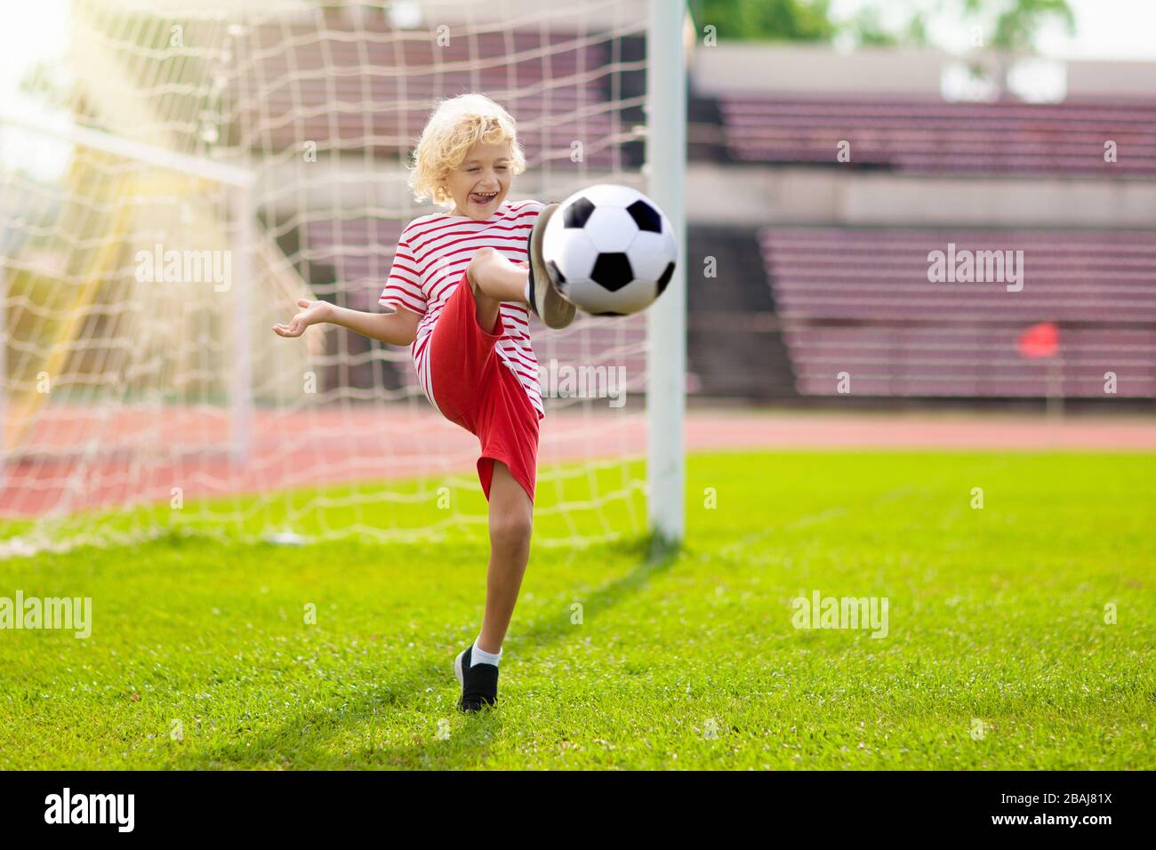 Kinder spielen auf dem Stadionfeld im Freien Fußball. Kinder erzielen ...