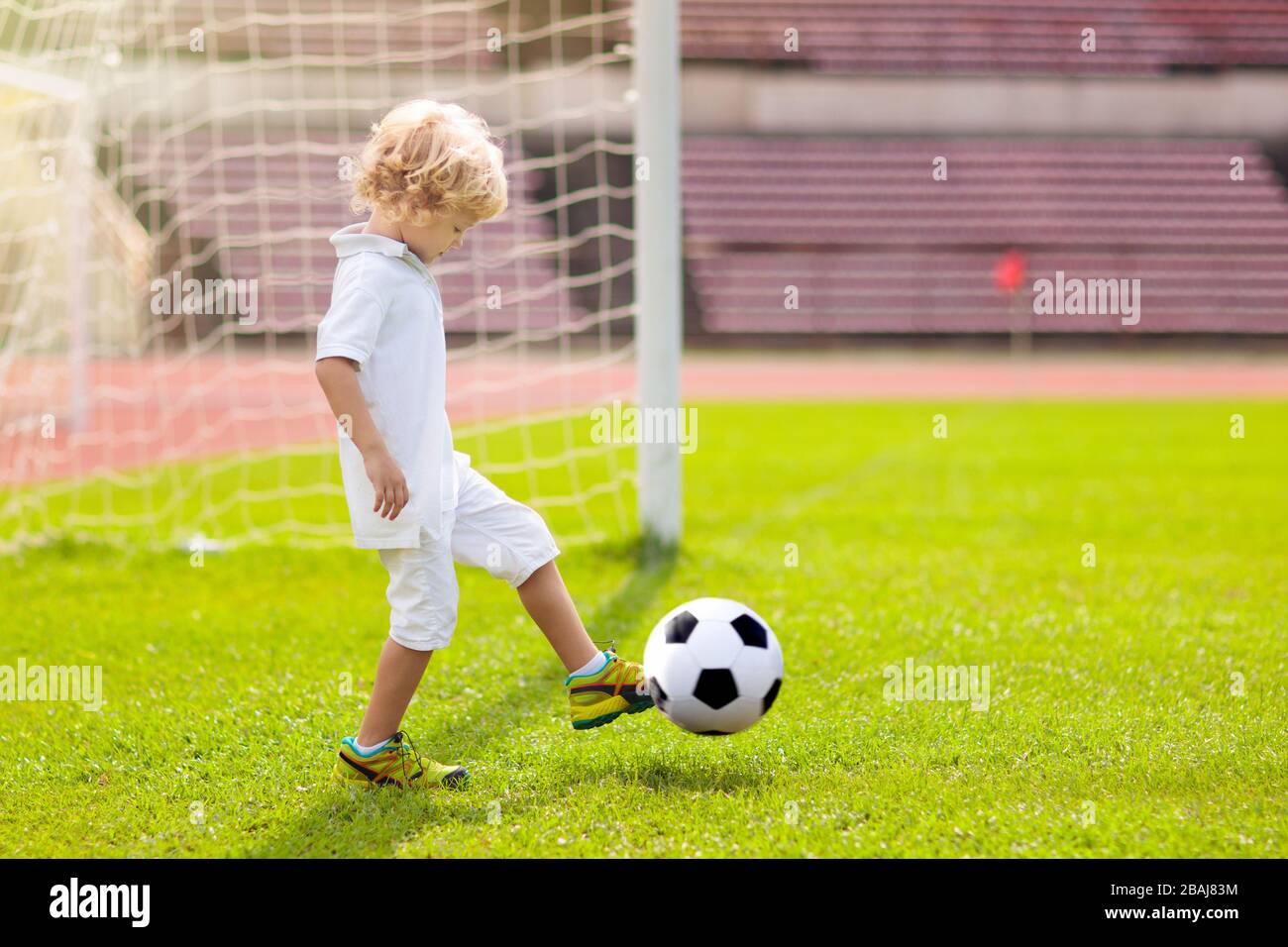 Kinder spielen auf dem Stadionfeld im Freien Fußball. Kinder erzielen ...