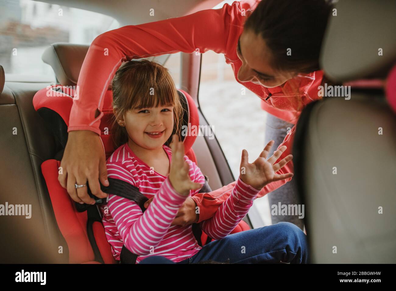 Das liebenswerte Mädchen, das von ihrem Kindermädchen in ihrem Autositz ...