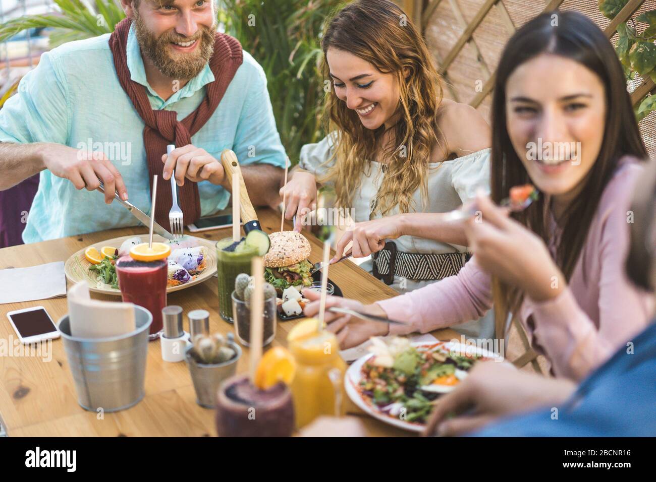 Junge Leute, die Brunch essen und Smoothies trinken, mit im Restaurant ...