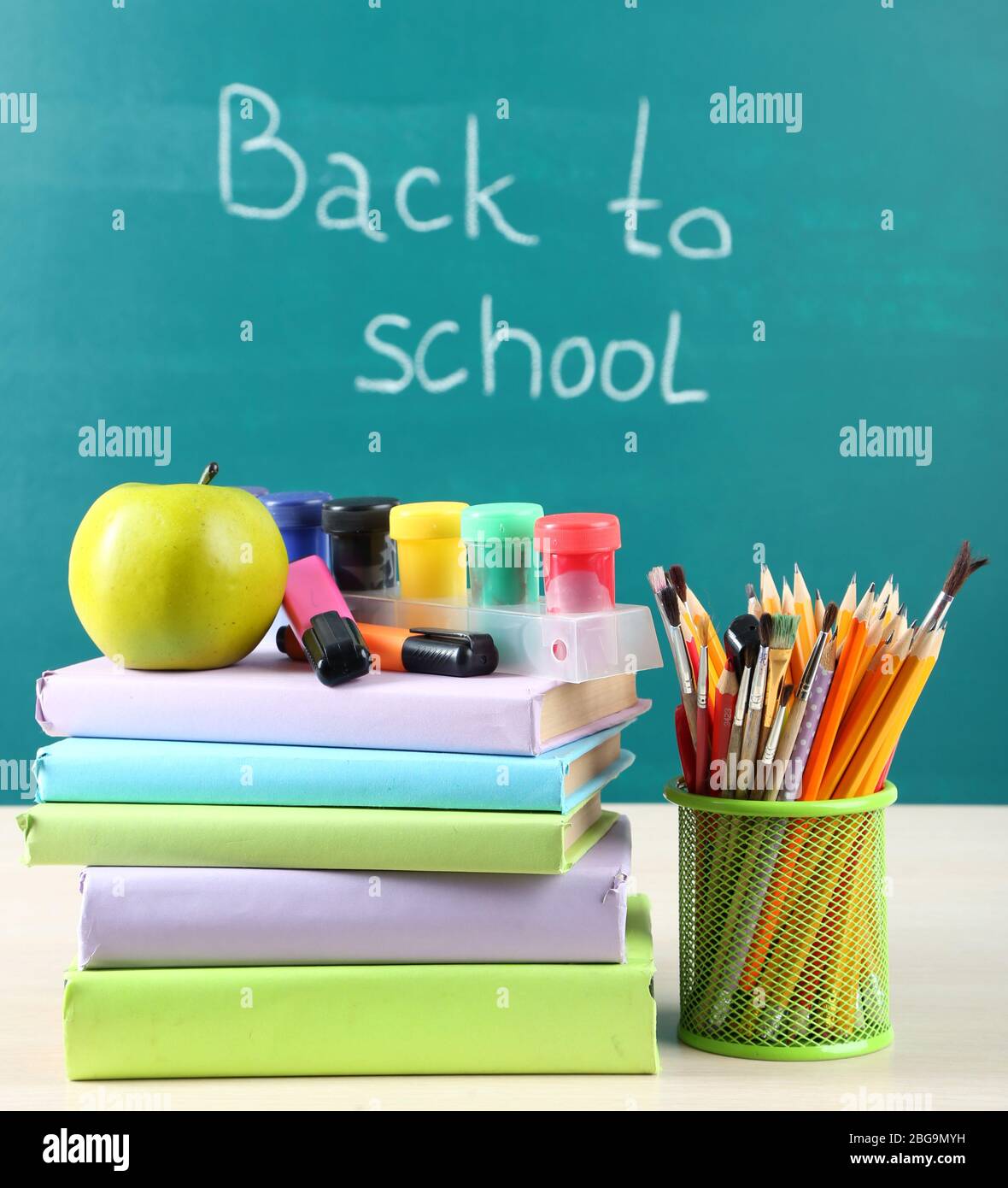 Schulbedarf auf Tisch auf Tafel Hintergrund Stockfotografie - Alamy