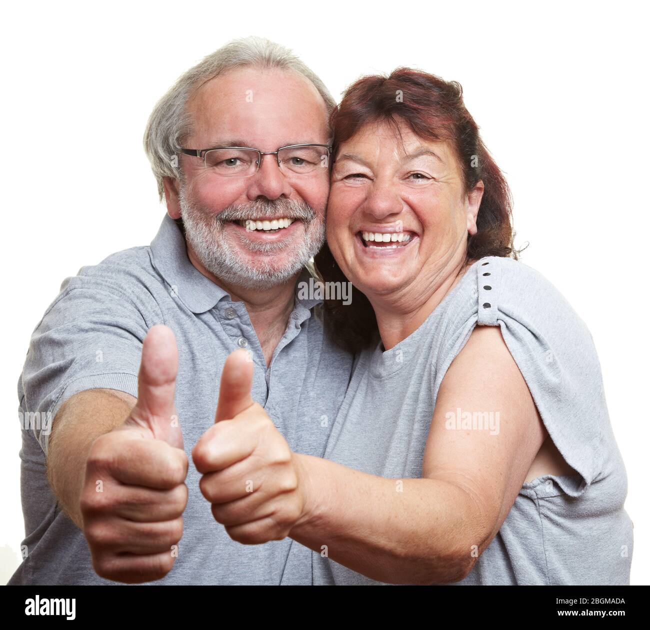 Zwei lachende, glückliche Senioren halten ihre Daumen hoch ...