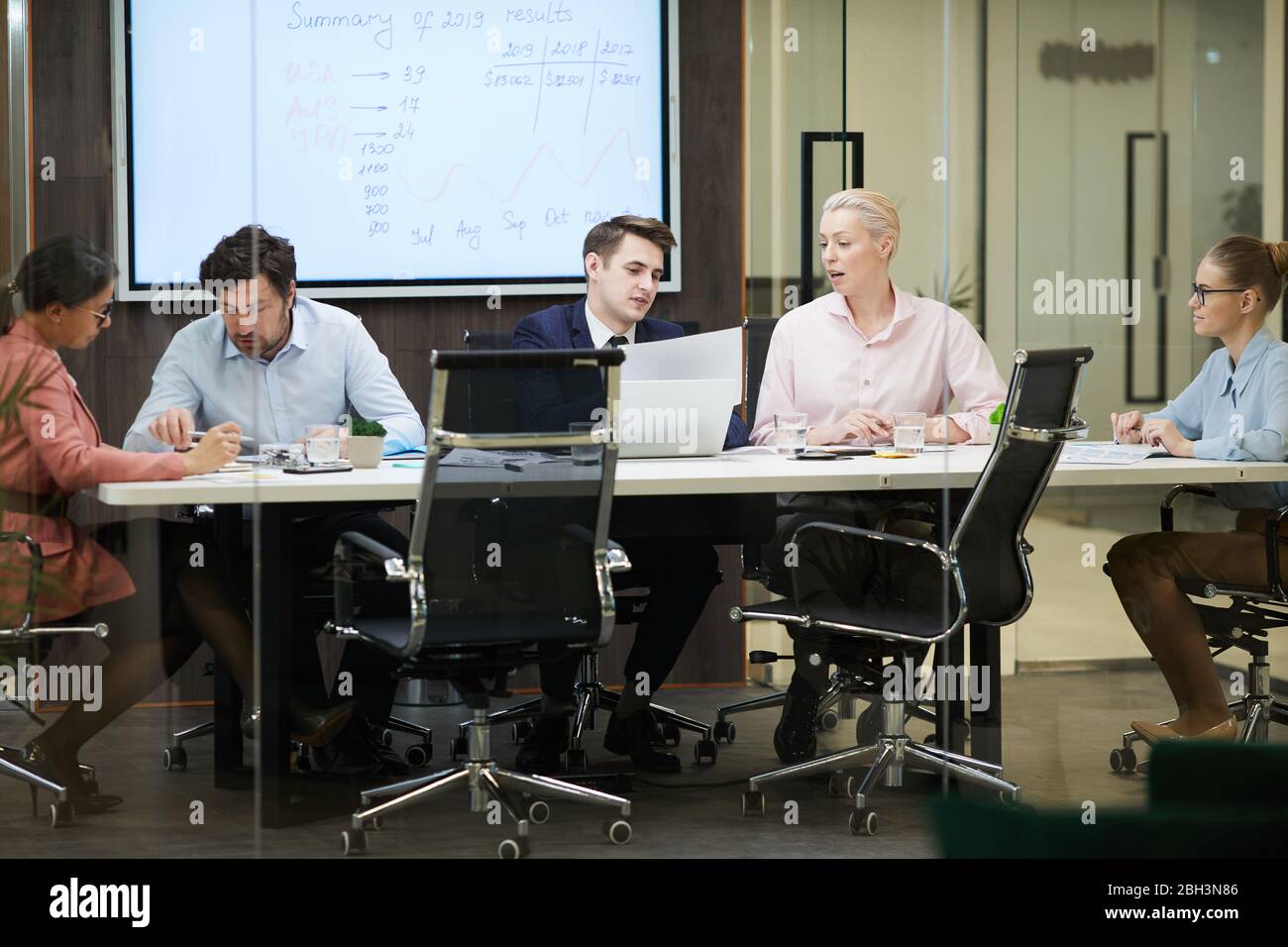 Eine Gruppe von Geschäftsleuten, die gemeinsam am Tisch arbeiten, während sie im Büro bei einer ...