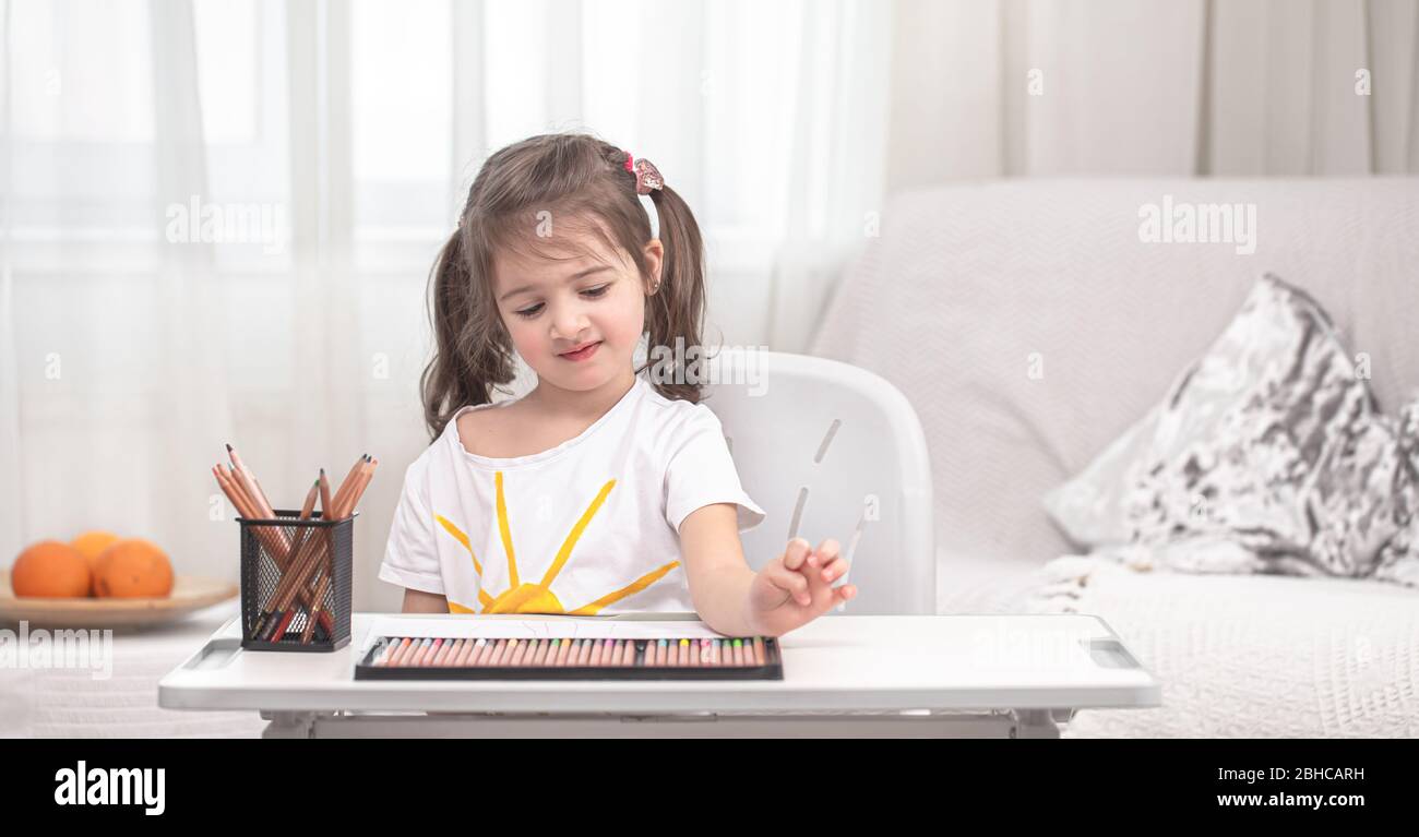 Das Mädchen sitzt am Tisch und macht Hausaufgaben. Das Kind lernt zu ...