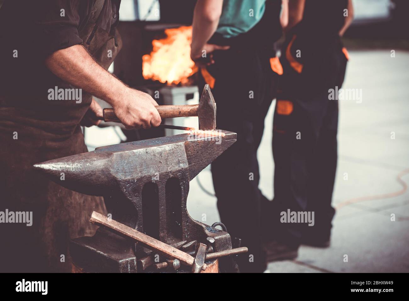 Der Schmied schmiedet das geschmolzene Metall auf dem Amboss in ...