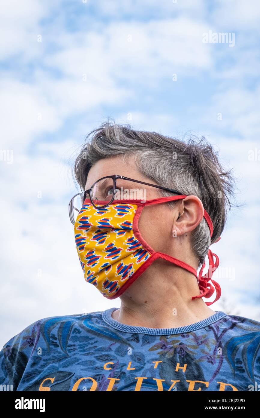Frau im mittleren Alter, 54 Jahre, mit grauen kurzen Haaren im blauen T-Shirt vor blauem Himmel ...