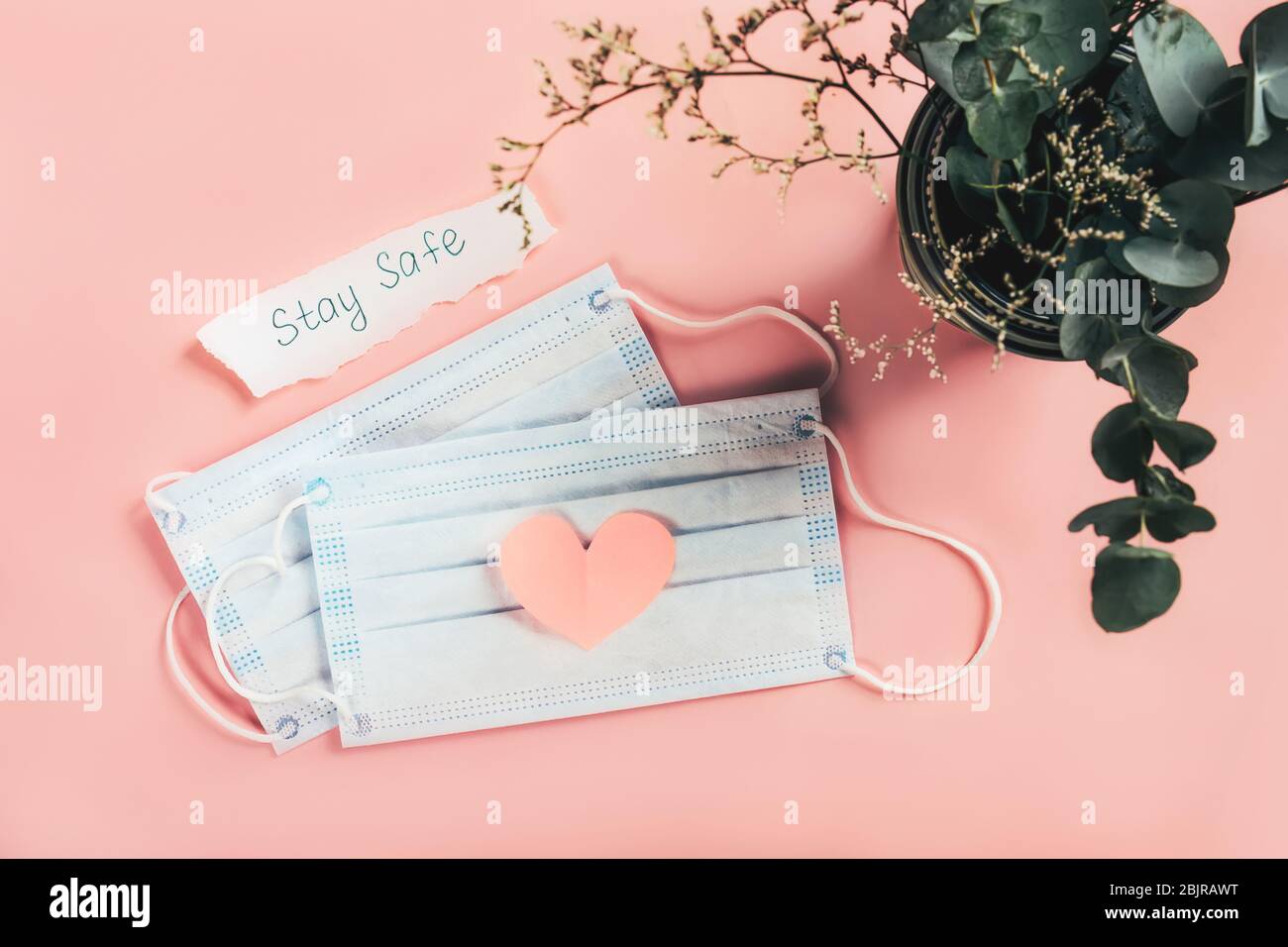 COVID-19. Gesichtsmaske mit einem Stück Papier mit Schild Bleib sicher ...