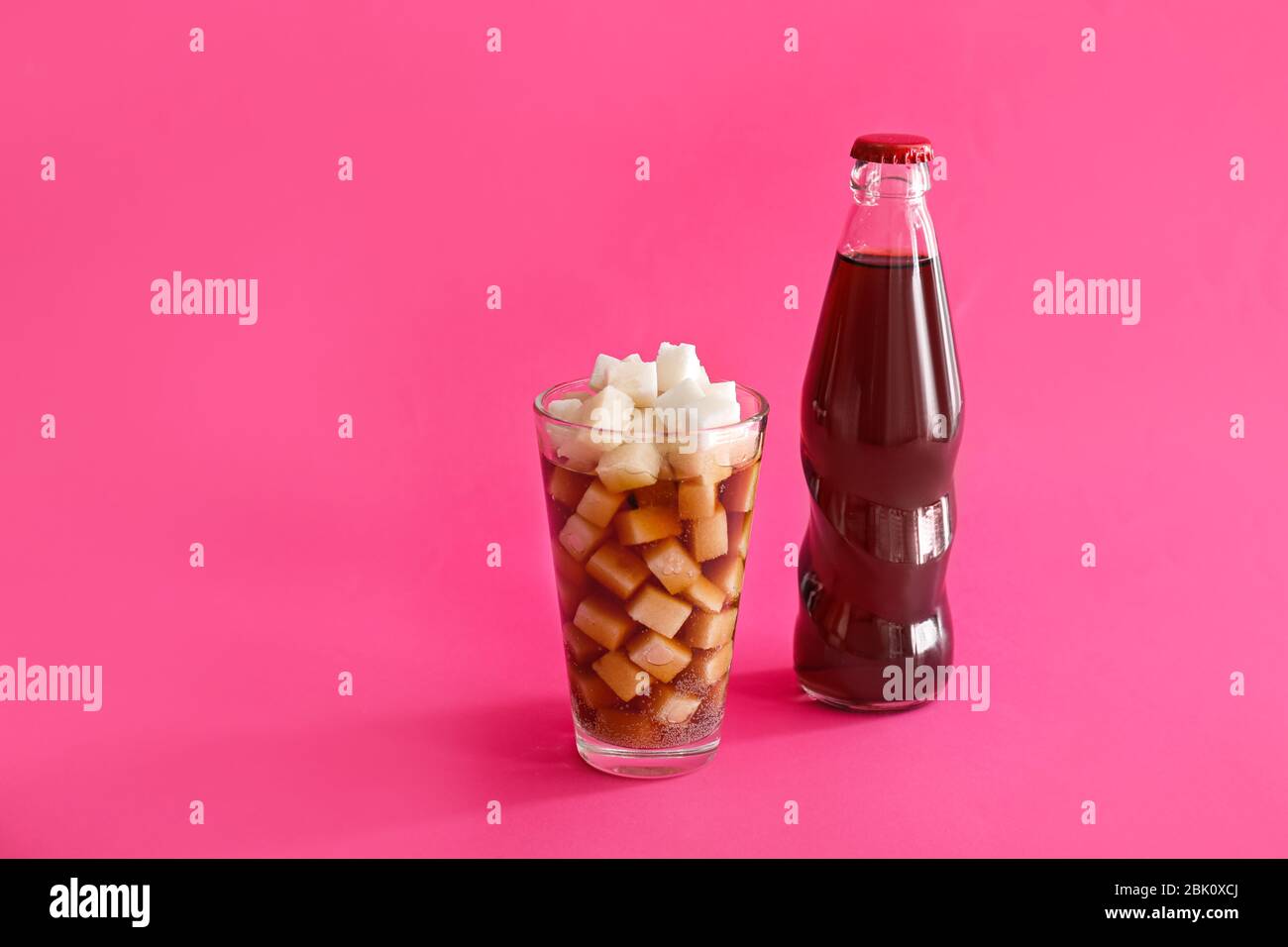 Flasche und Glas Cola mit Zucker Würfel auf farbigen Hintergrund ...