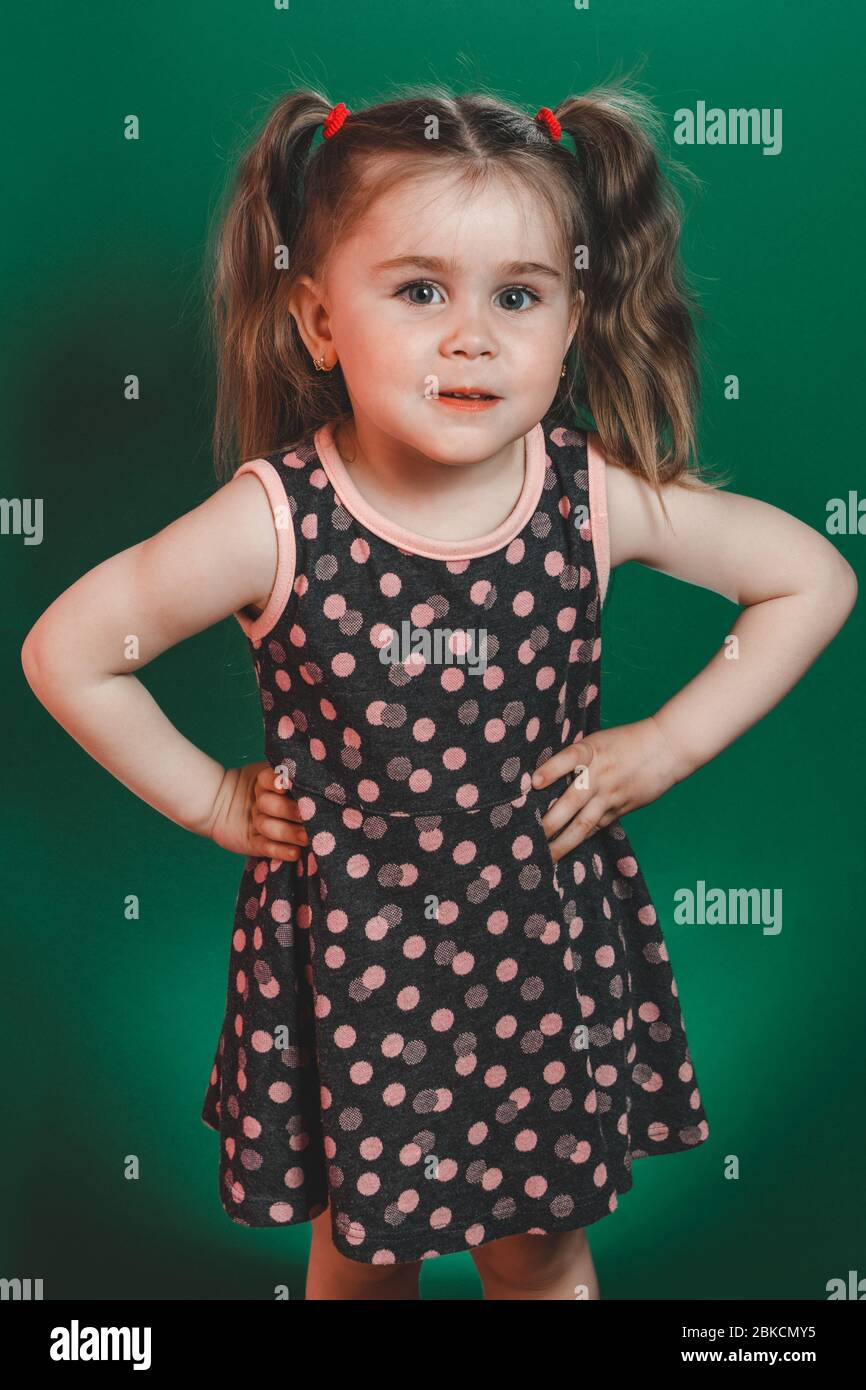 Kleines Mädchen von drei Jahren mit Schwänzen im Kleid posiert im ... Kleines Mädchen von drei Jahren mit Schwänzen im Kleid posiert im ...
