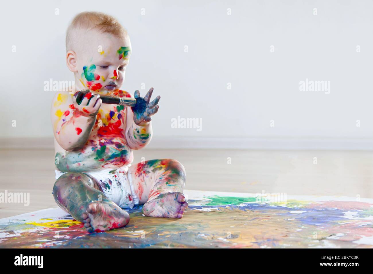 Baby Kind zeichnet mit farbigen Farben Hände, schmutzige Füße und ...