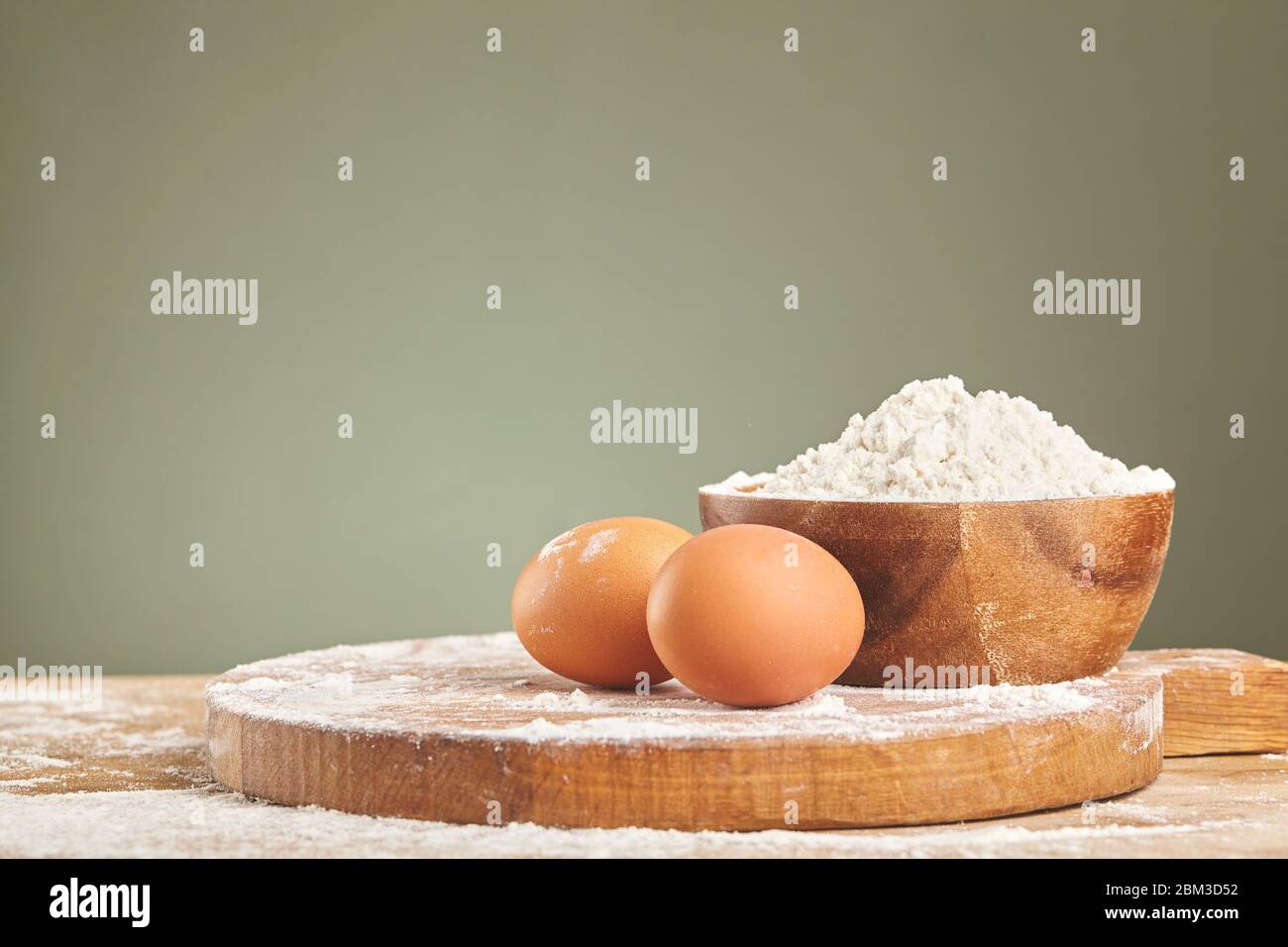Mehl in der Schüssel mit Eiern auf Holzbrett. Nahaufnahme ...