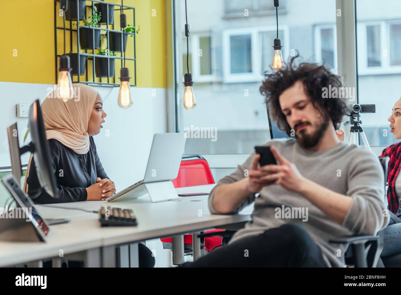 Bärtiger Angestellter mit Afro-Haarschnitt, der auf seinem Telefon ...