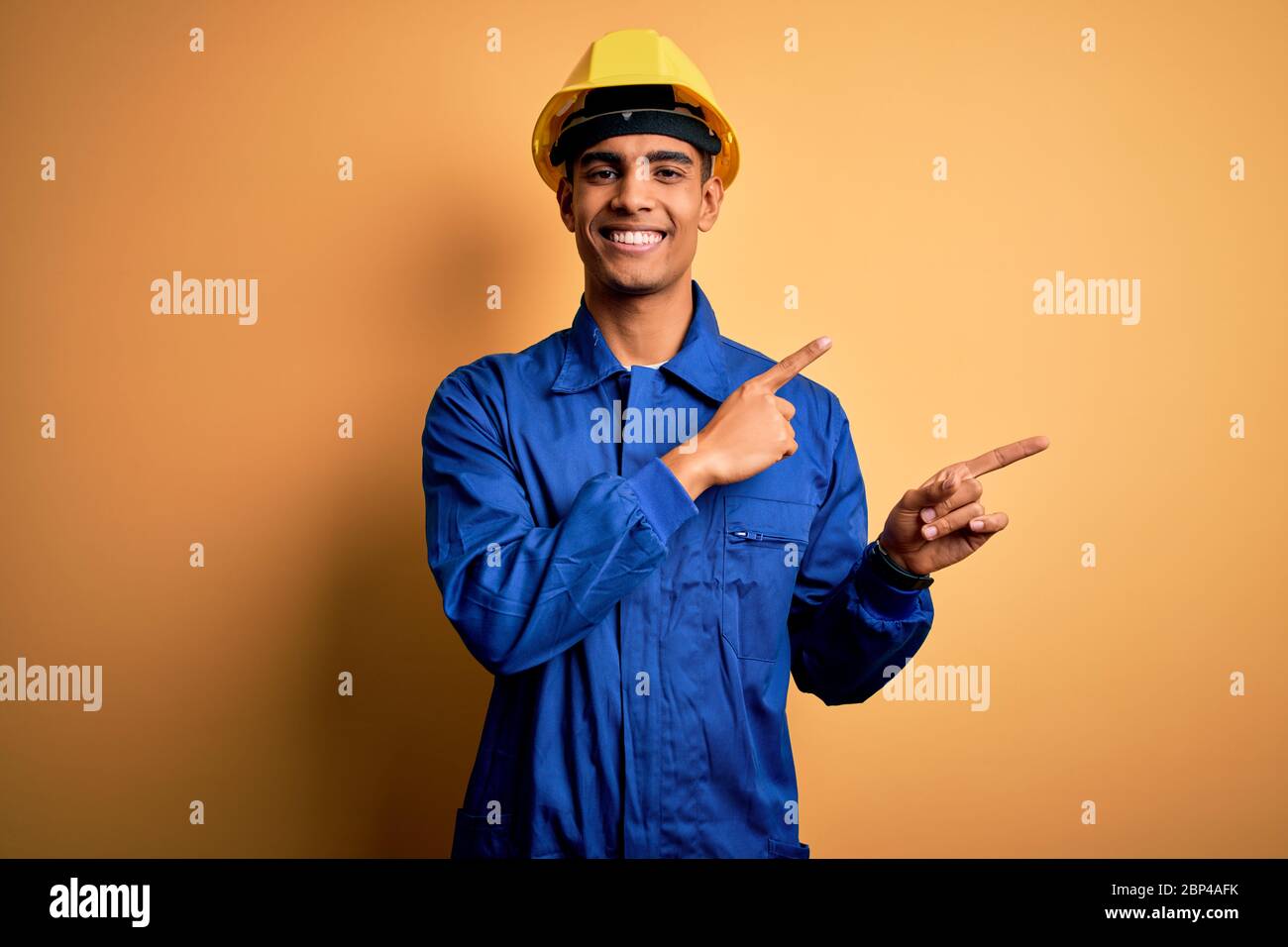 Junger, gutaussehender afroamerikanischer Arbeiter, der blaue Uniform ... Junger, gutaussehender afroamerikanischer Arbeiter, der blaue Uniform ...