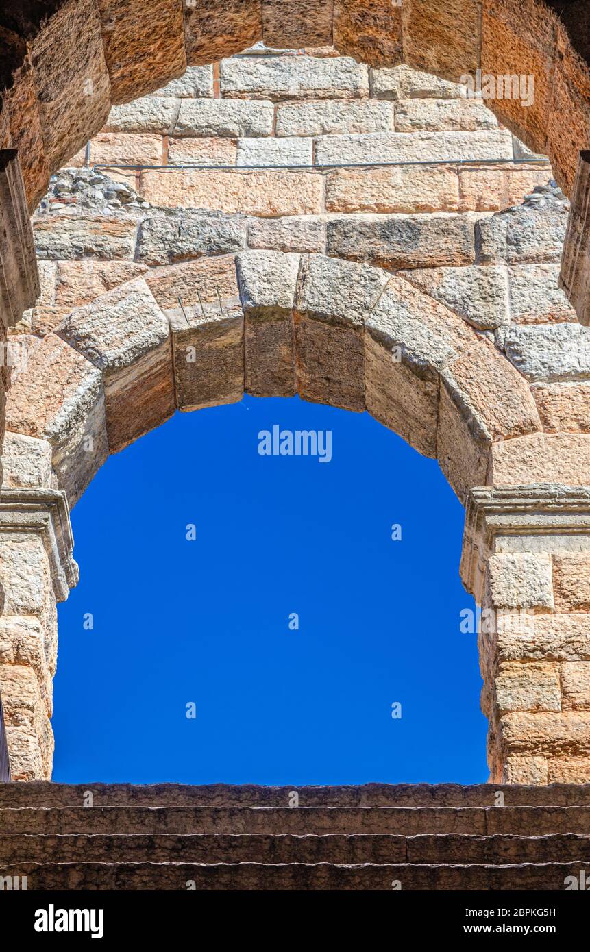 Blauer klarer Himmel durch Kalkstein Backstein Bogenfenster der Arena ...
