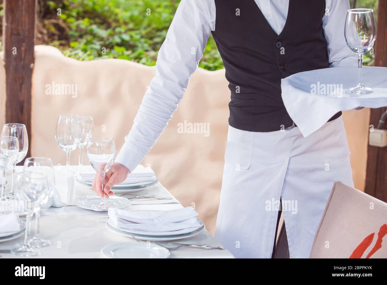 Der Kellner arbeitet in einem Restaurant auf der Sommerterrasse ...