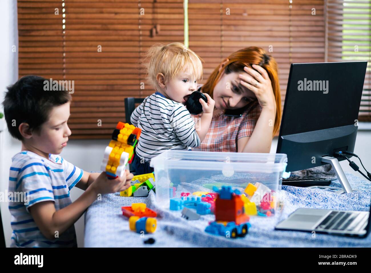 Mama mit zwei kleinen Jungen auf den Knien versucht zu Hause zu lachen ...
