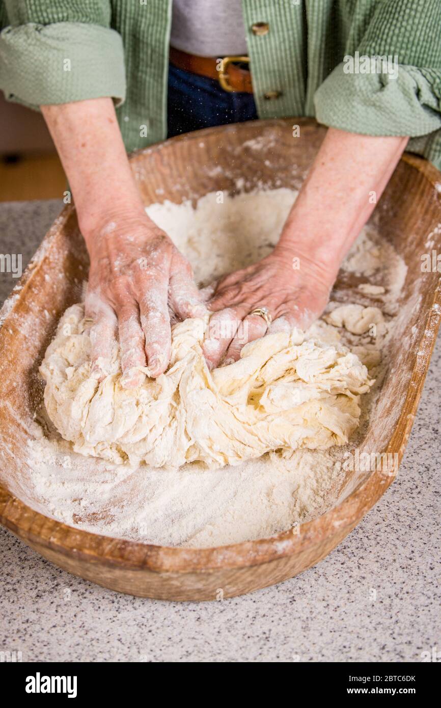 Frau Kneten Teig in einem Teigtrog, bis es glatt und elastisch ist, als ...