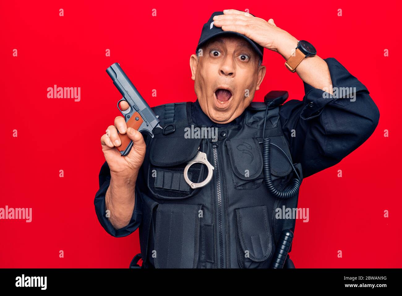 Älterer Mann mit grauen Haaren in Polizeiuniform, der Waffe hält ...