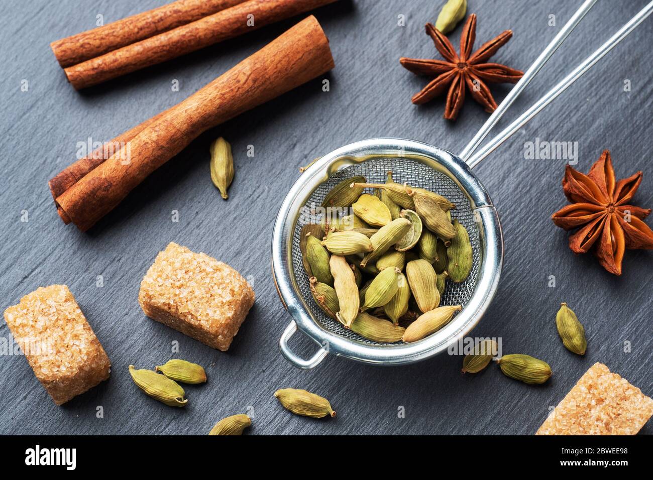 Ganze Kardamom-Körner, ein Stock Zimt-Sternanis und Rohrzucker ...