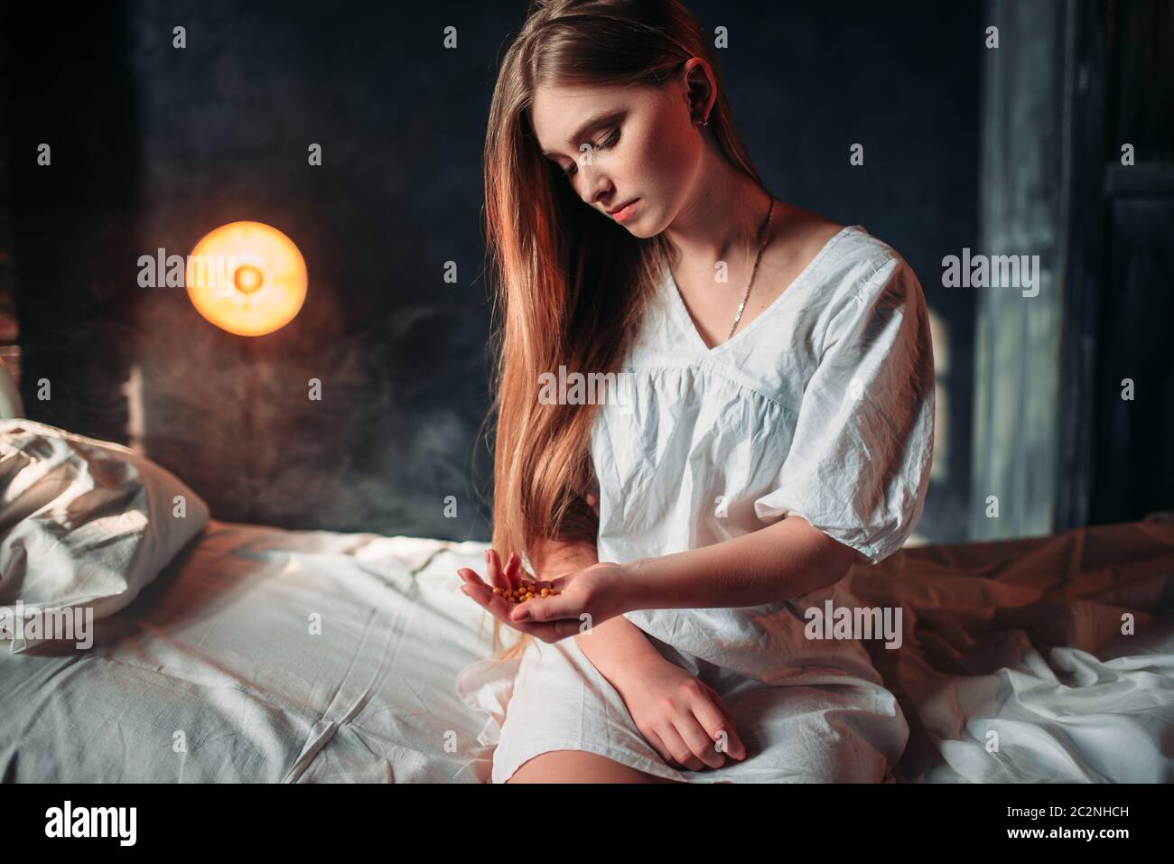Junge kranke Frau sitzt am Krankenhausbett mit Drogen in der hand ...