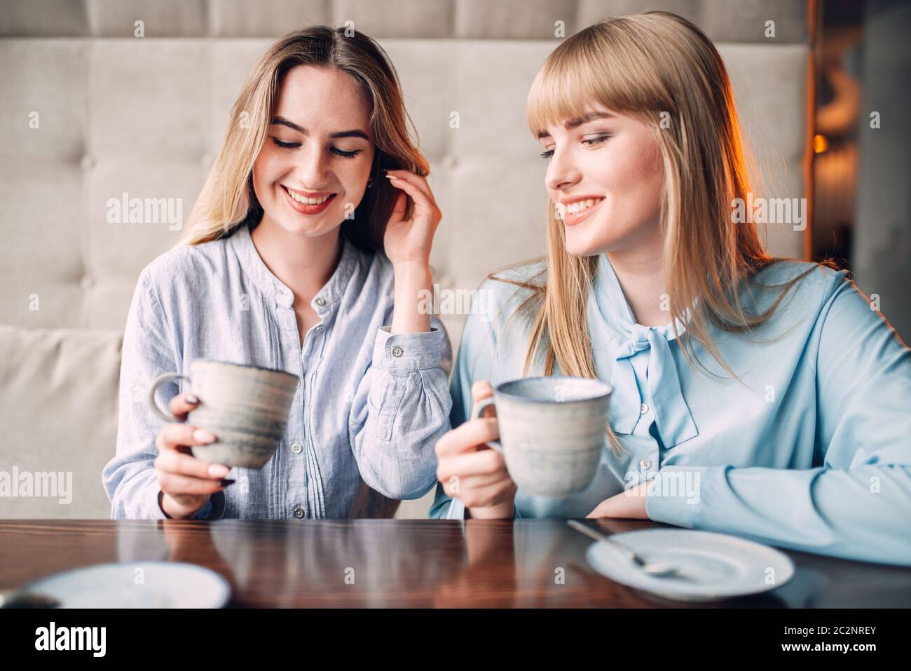 Zwei lächelnde Freundinnen trinkt Kaffee am Tisch im Café. Weibliche ...