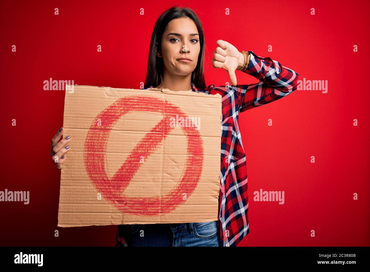 Junge schöne Brünette Frau hält Banner mit verbotenen Signal über rotem ... Junge schöne Brünette Frau hält Banner mit verbotenen Signal über rotem ...