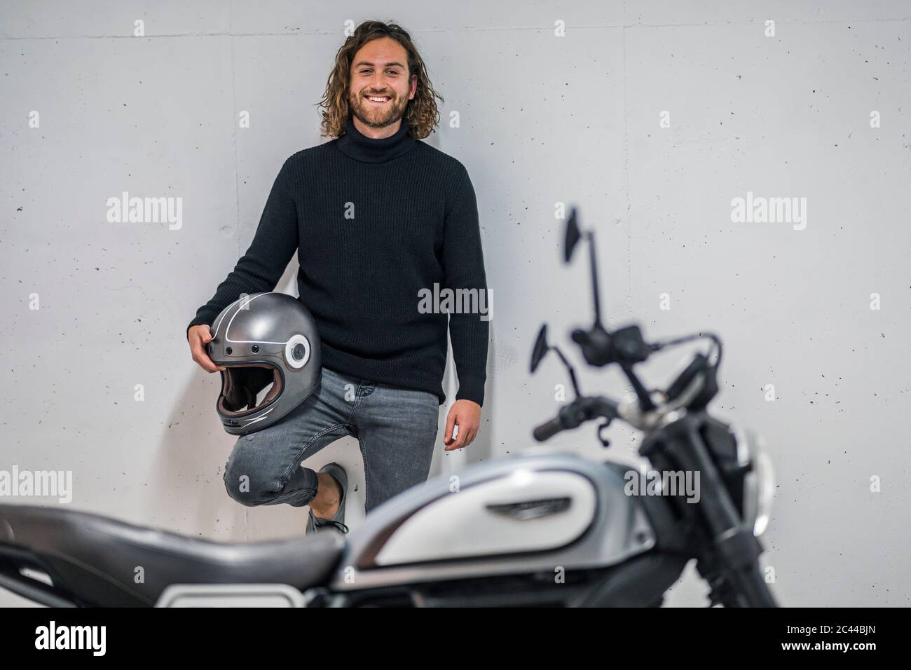 Junger Mann mit Helm hinter Motorrad Stockfotografie - Alamy