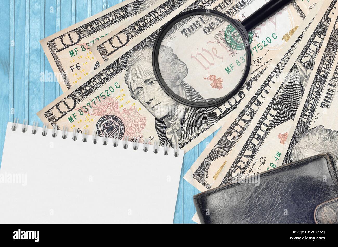 10 US-Dollar Scheine und Lupe mit schwarzem Geldbeutel und Notizblock ...
