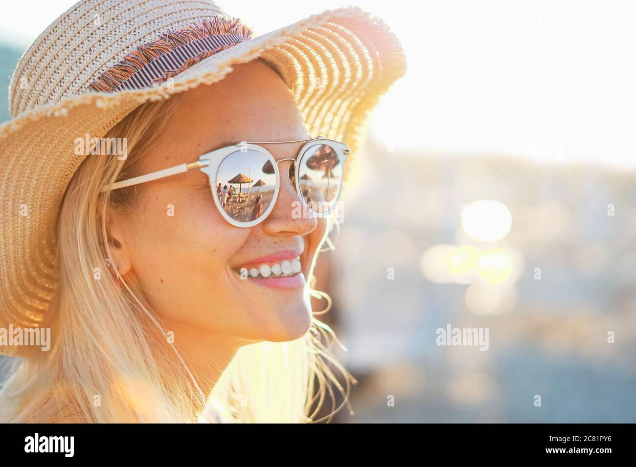 Ein blondes Mädchen lächelt mit Hut auf - Strand und Sonnenlicht ... Ein blondes Mädchen lächelt mit Hut auf - Strand und Sonnenlicht ...