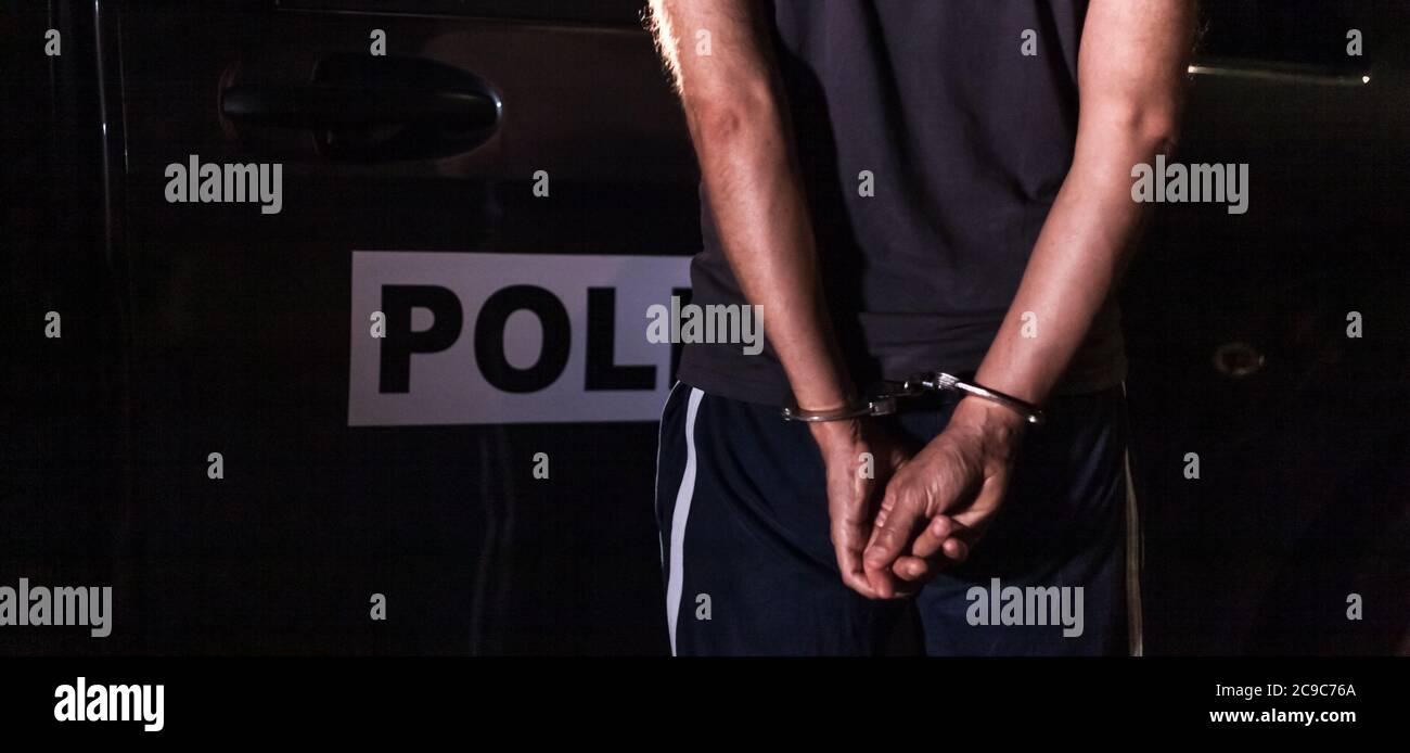 Verbrecher mit Handschellen vor einem Polizeiauto Stockfotografie - Alamy