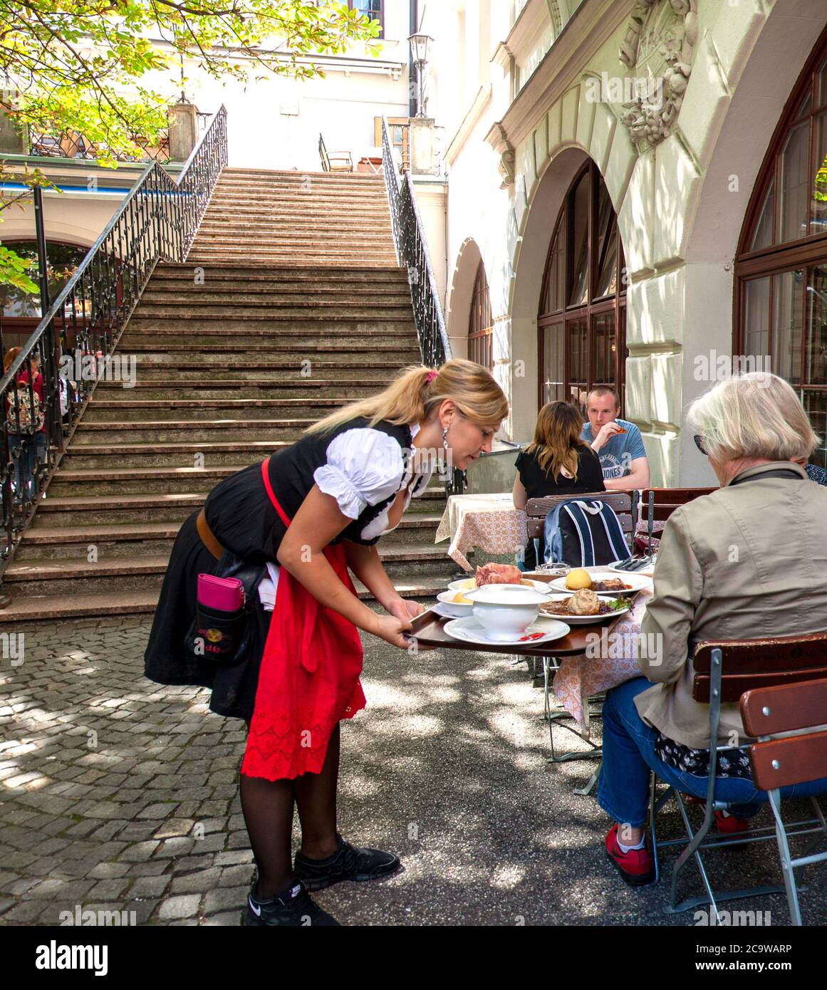 Eine Kellnerin serviert einem Kunden Mittagessen, Biergarten im Freien ...