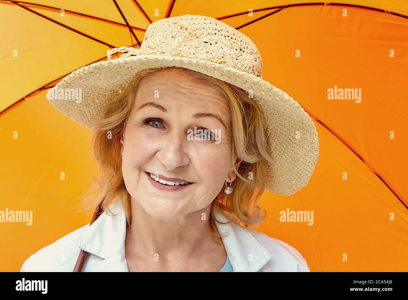 Ältere weiße attraktive blonde Frau etwa 62 Jahre alt im Hut steht ...