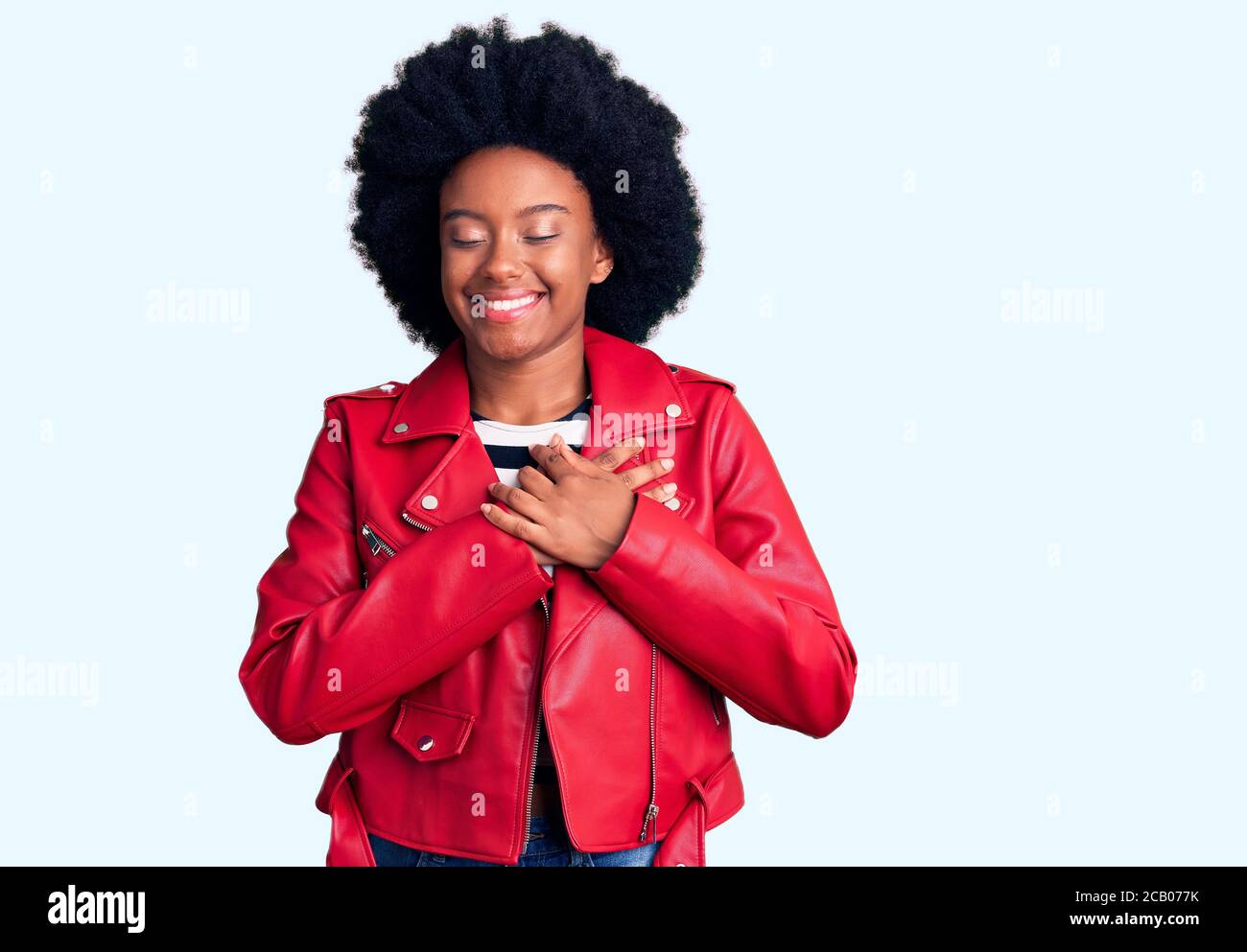 Junge afroamerikanische Frau trägt rote Lederjacke lächelnd mit Händen ...