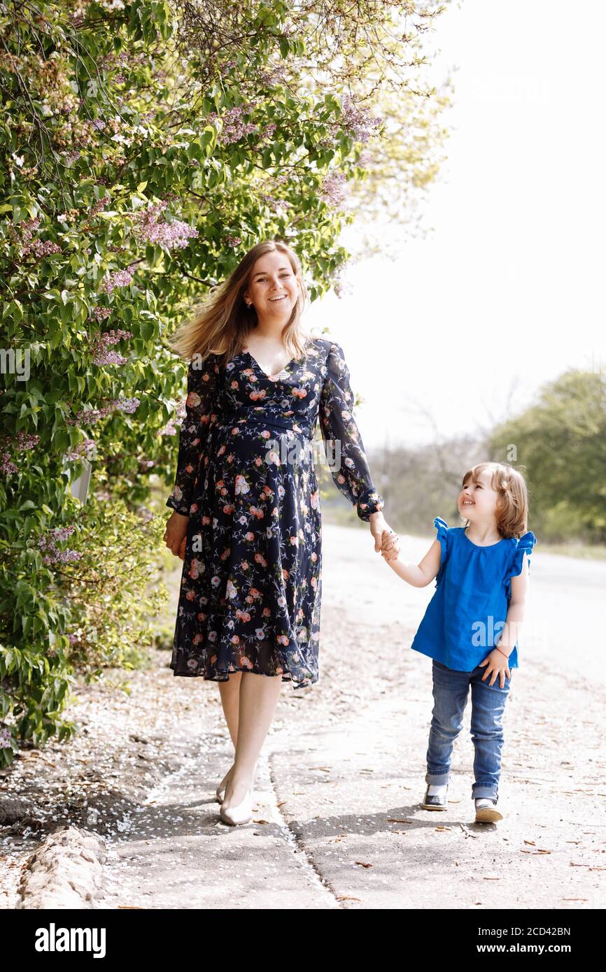 Portrait der glücklichen Familie. Schwangere Mutter und kleine Tochter gehen im Frühling ...