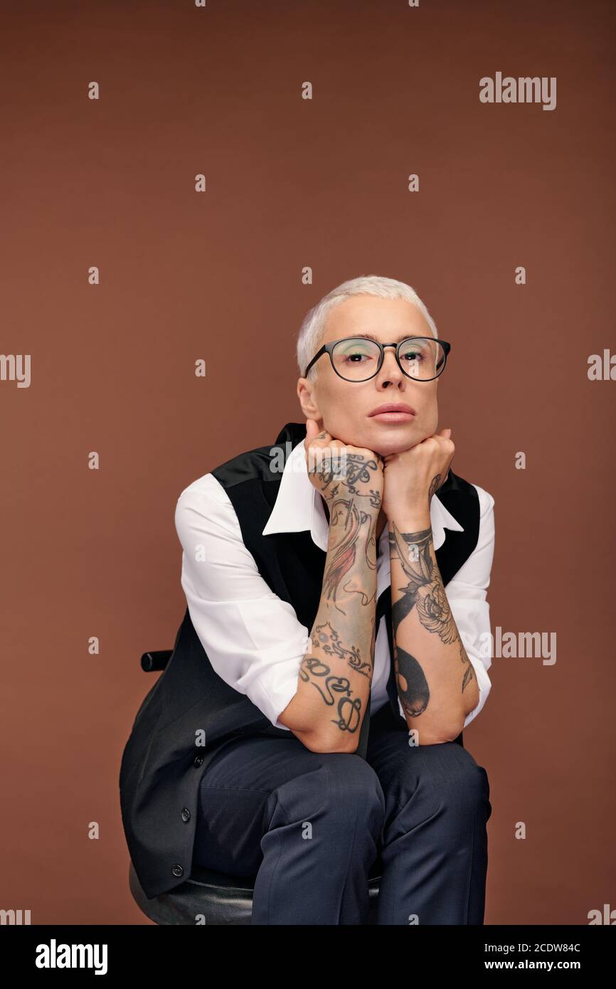 Junge Blonde Frau Mit Kurzen Haaren Und Armen Bedeckt Mit Tattoos Sitzen Auf Einem Stuhl