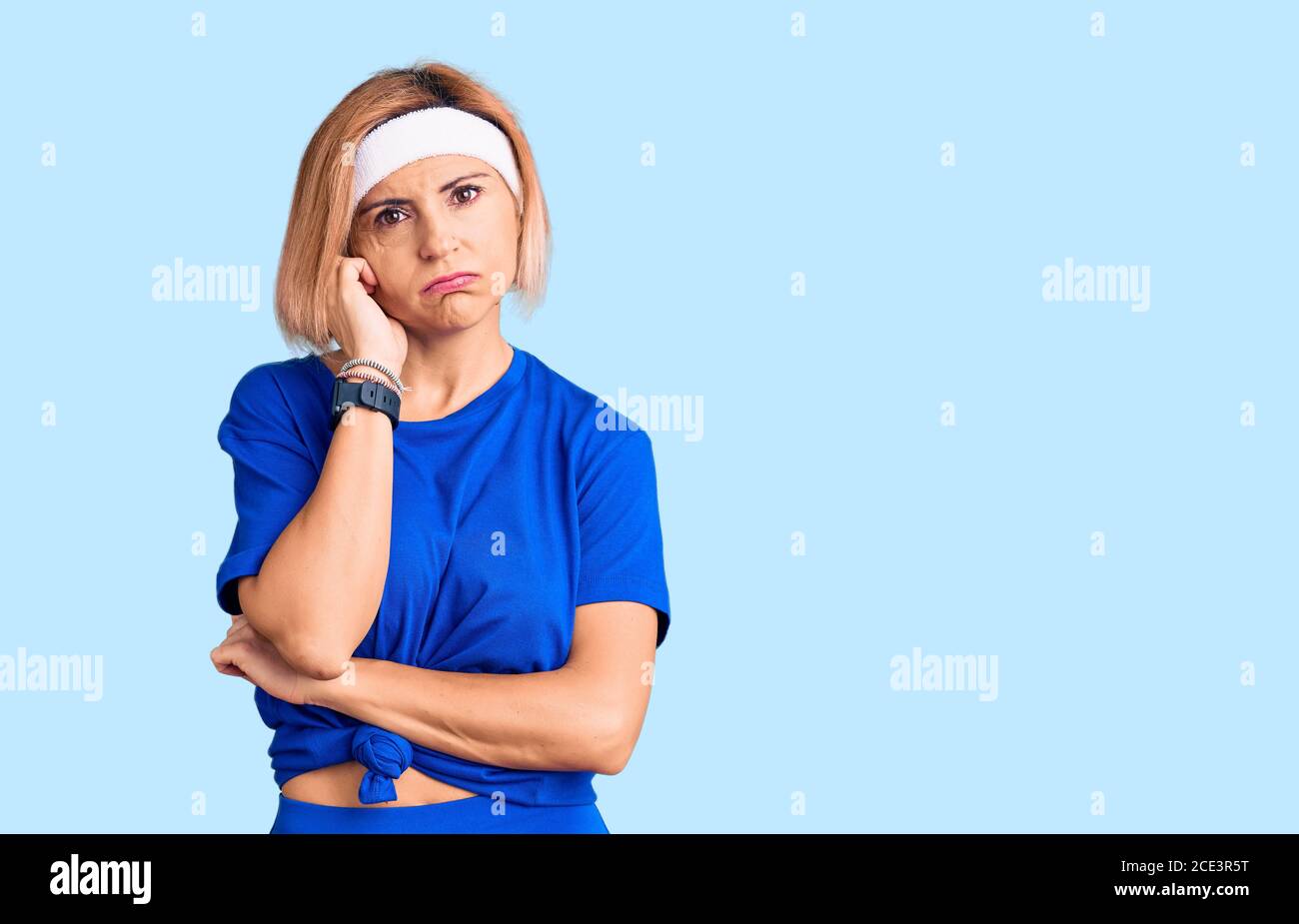 Junge blonde Frau trägt Sportkleidung Denken müde aussehen und ... Junge blonde Frau trägt Sportkleidung Denken müde aussehen und ...