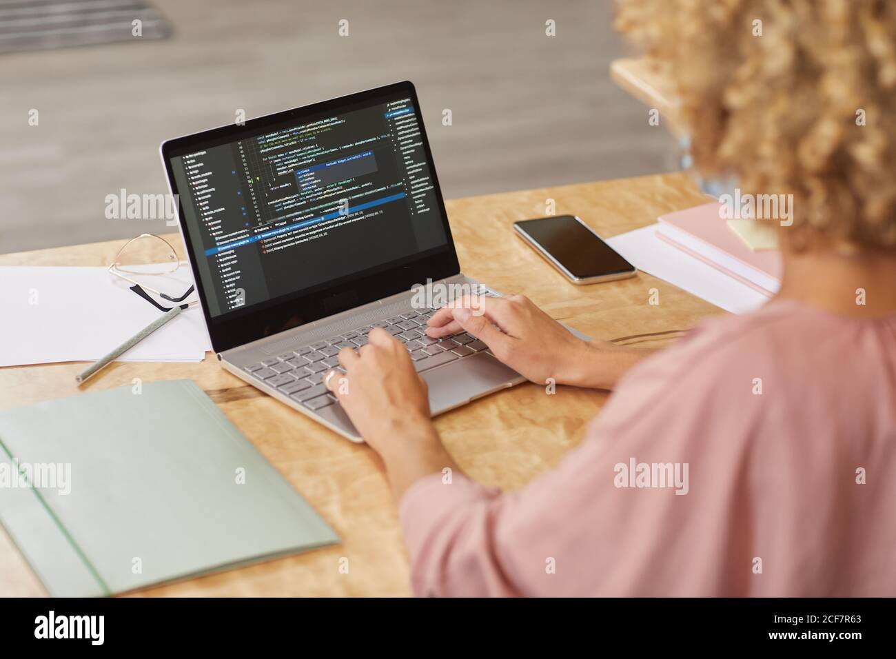 Rückansicht des Programmierers, der am Tisch sitzt und tippt Auf Laptop ...