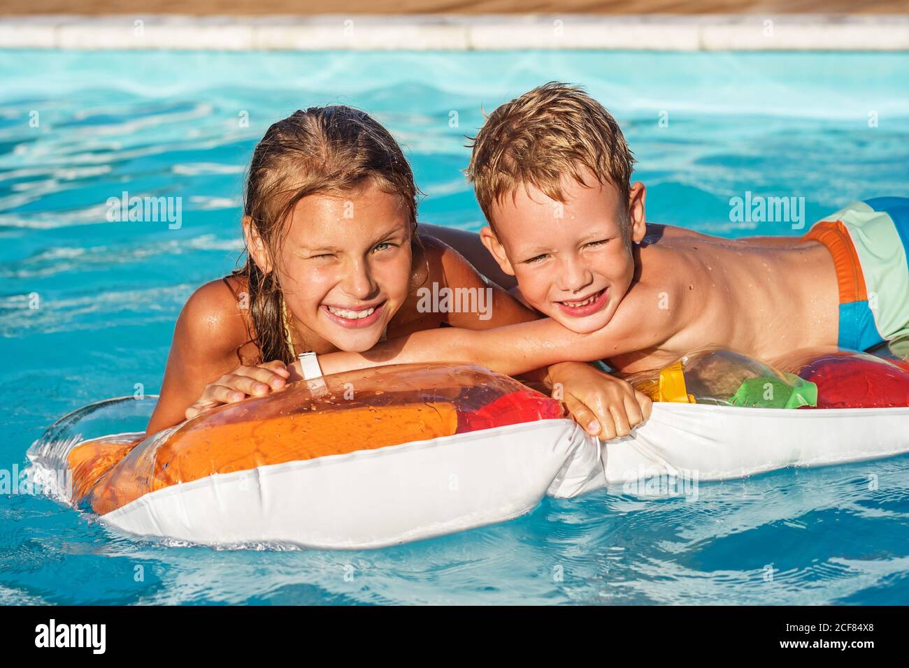 Kleine Kinder auf aufblasbarer Matratze im Pool. Lächelnde Kinder spielen und Spaß haben im Pool ...