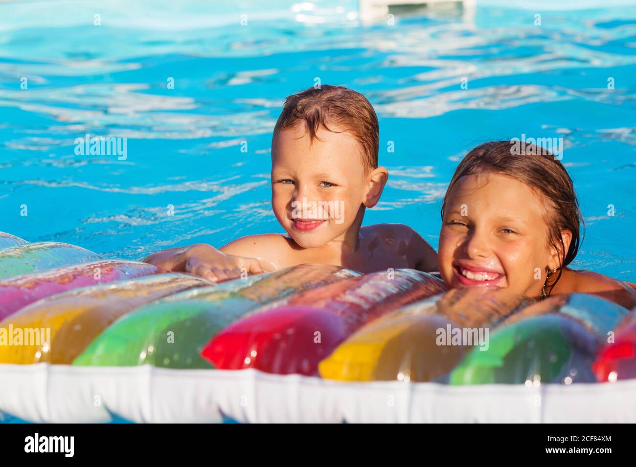 Kleine Kinder spielen und Spaß haben im Schwimmbad mit Luftmatratze. Kinder spielen im Wasser ...
