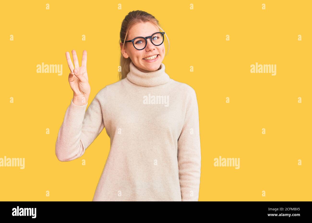 Junge schöne blonde Frau trägt Rollkragenpullover und Brille zeigt Und ... Junge schöne blonde Frau trägt Rollkragenpullover und Brille zeigt Und ...