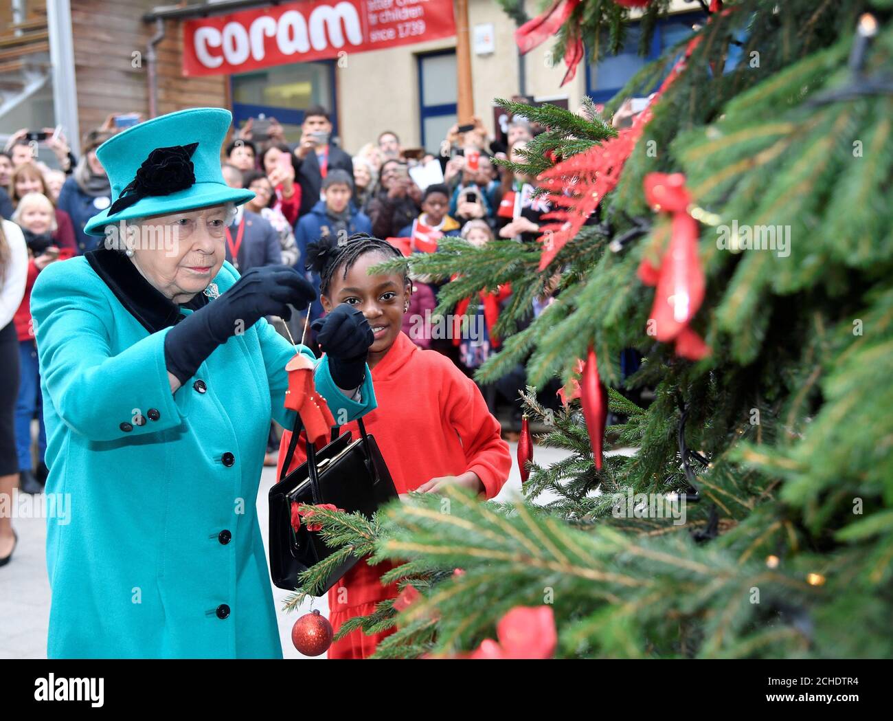 Queen Elizabeth II. Und Shylah Gordon, 8 Jahre alt, befestigen eine ...