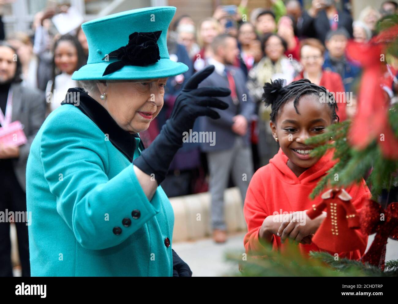 Queen Elizabeth II. Und Shylah Gordon, 8 Jahre alt, befestigen eine ...