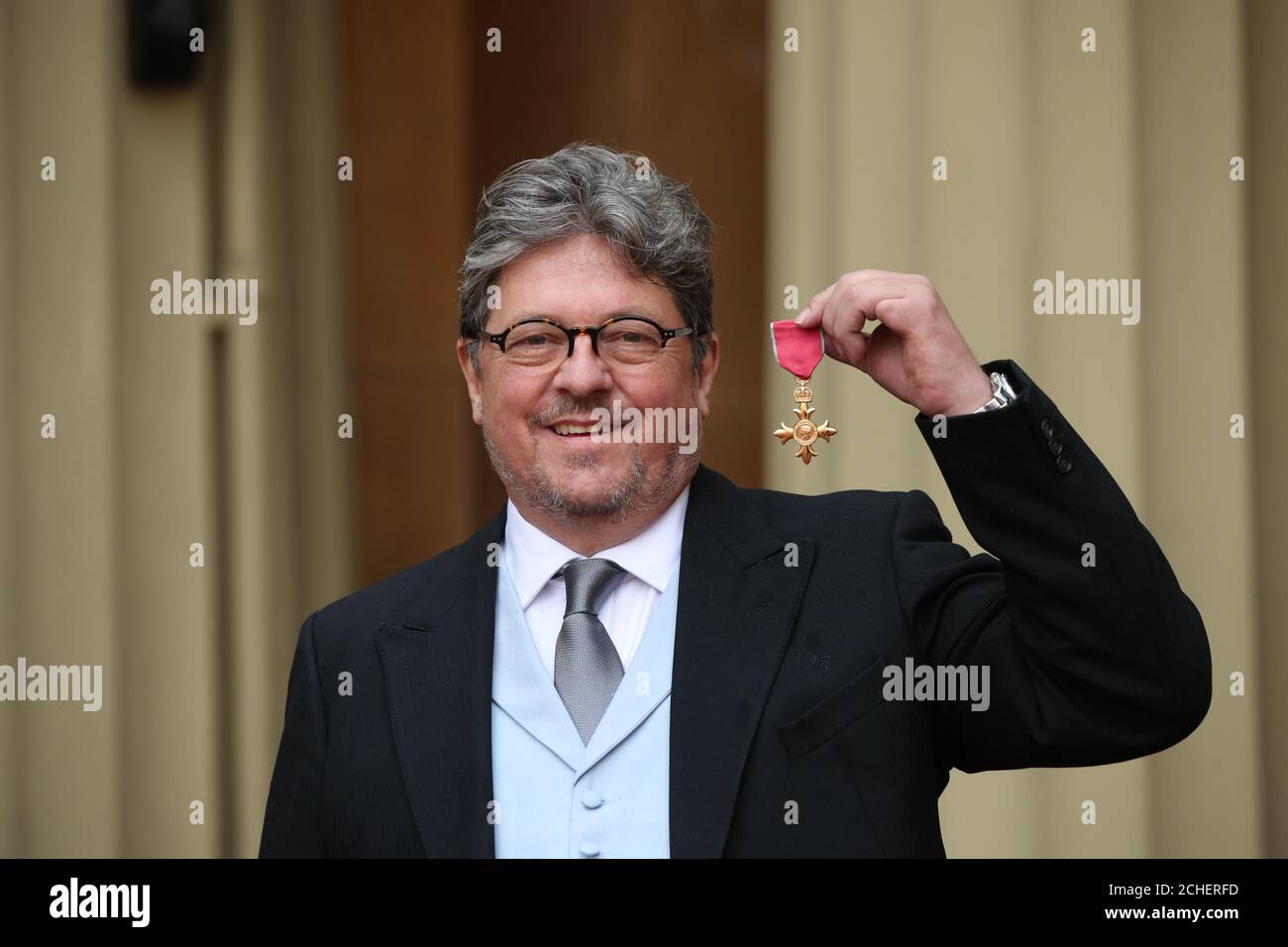Der plastische Chirurg Professor Simon Kay hält seine OBE nach einer ...
