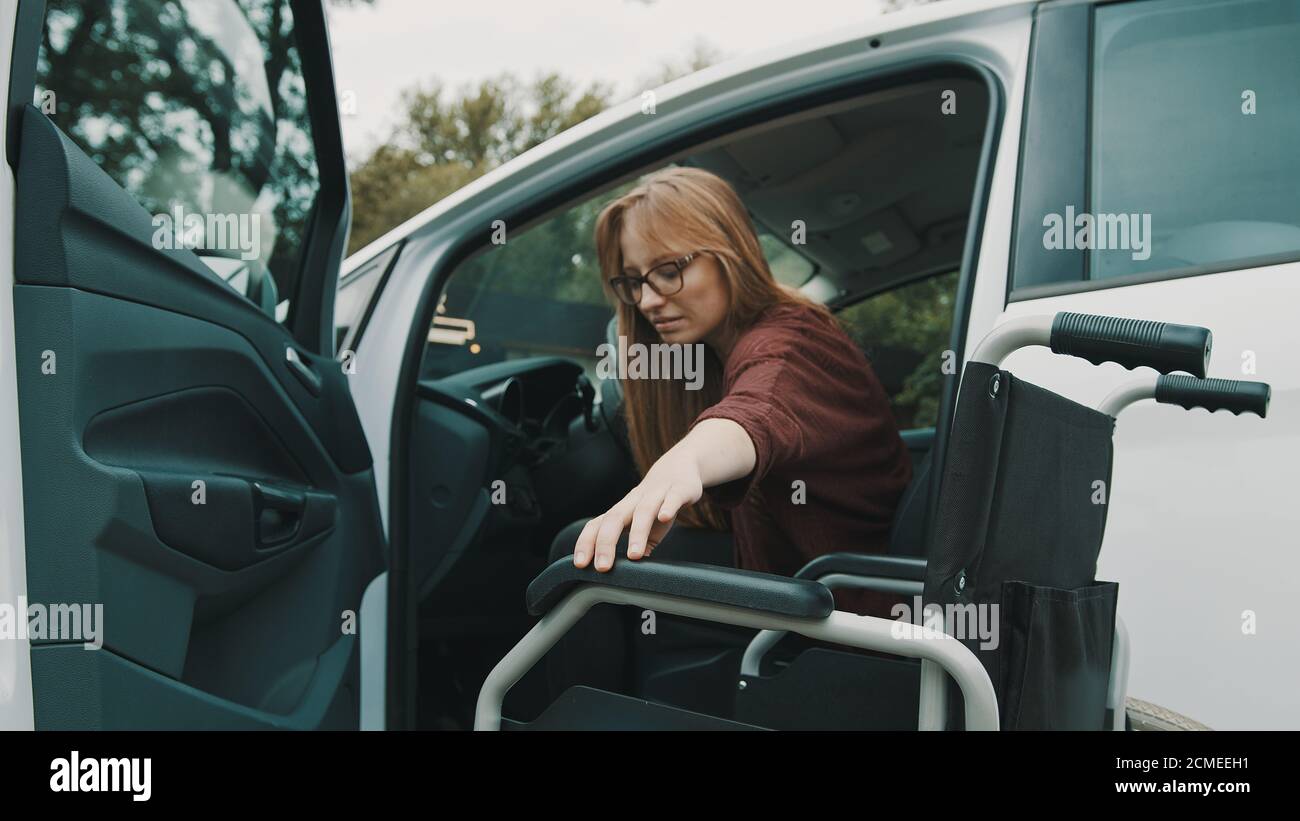 Junge behinderte Person, die im Rollstuhl aus dem Auto aussteigen ...