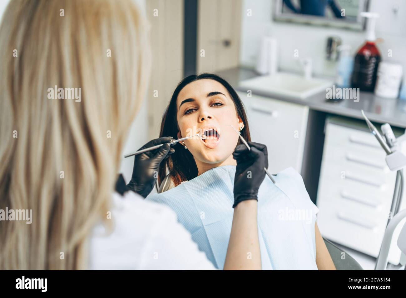 Ziemlich junge weibliche Zahnarzt macht Untersuchung und Behandlung für junge Weibliche ...