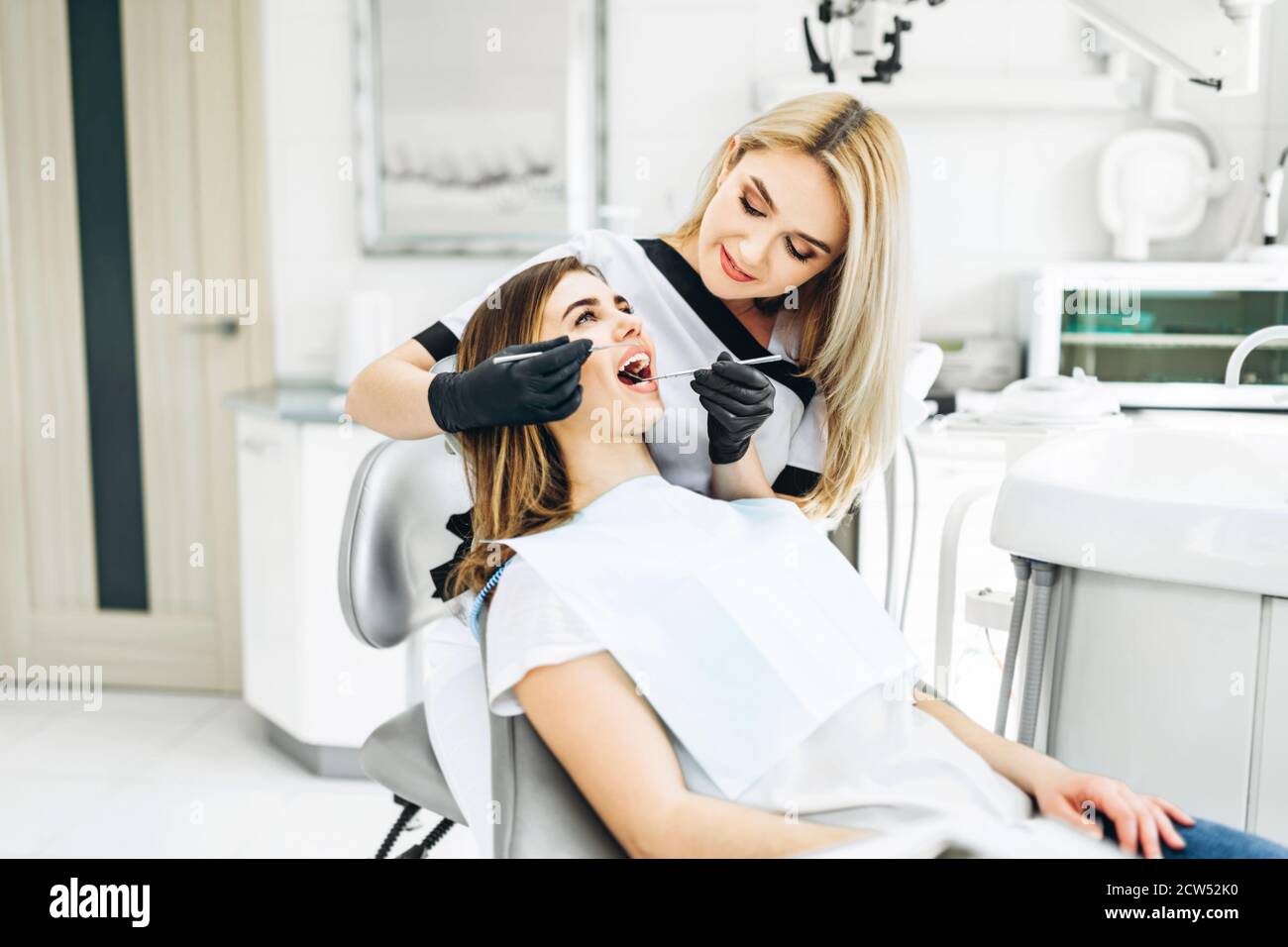 Ziemlich junge weibliche Zahnarzt macht Untersuchung und Behandlung für junge Weibliche ...