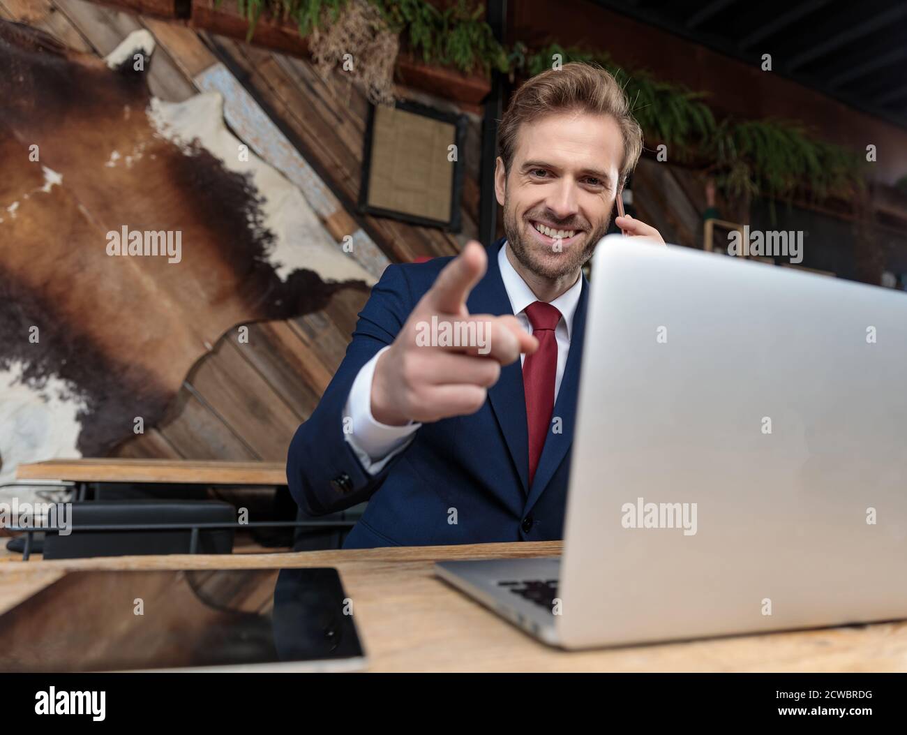 Junger Geschäftsmann, der am Telefon spricht und mit dem Finger zeigt ...