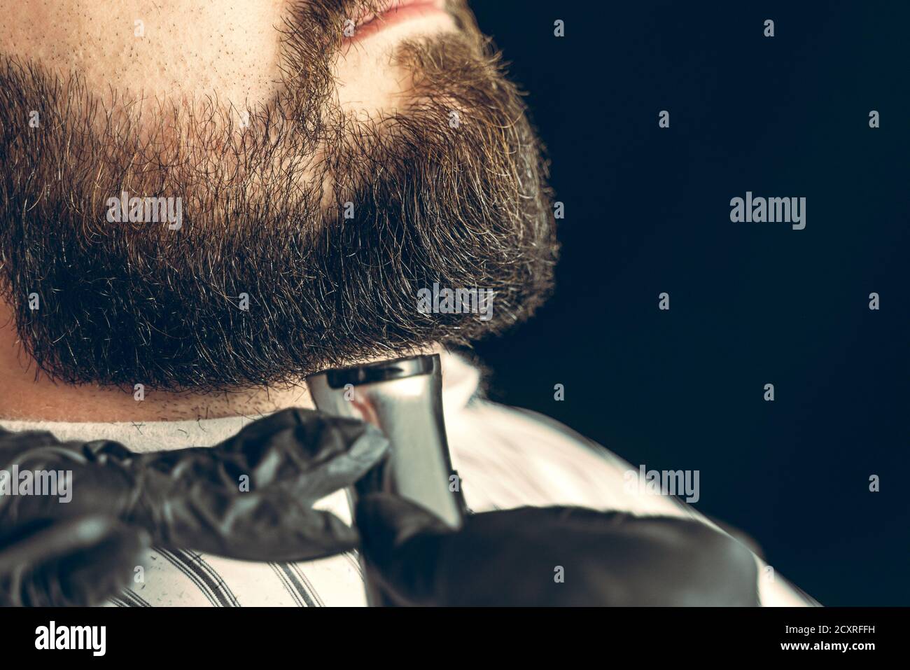 Barbershop-Kunde. Mann, der seinen Bart mit einem elektrischen Rasiermesser getrimmt ...