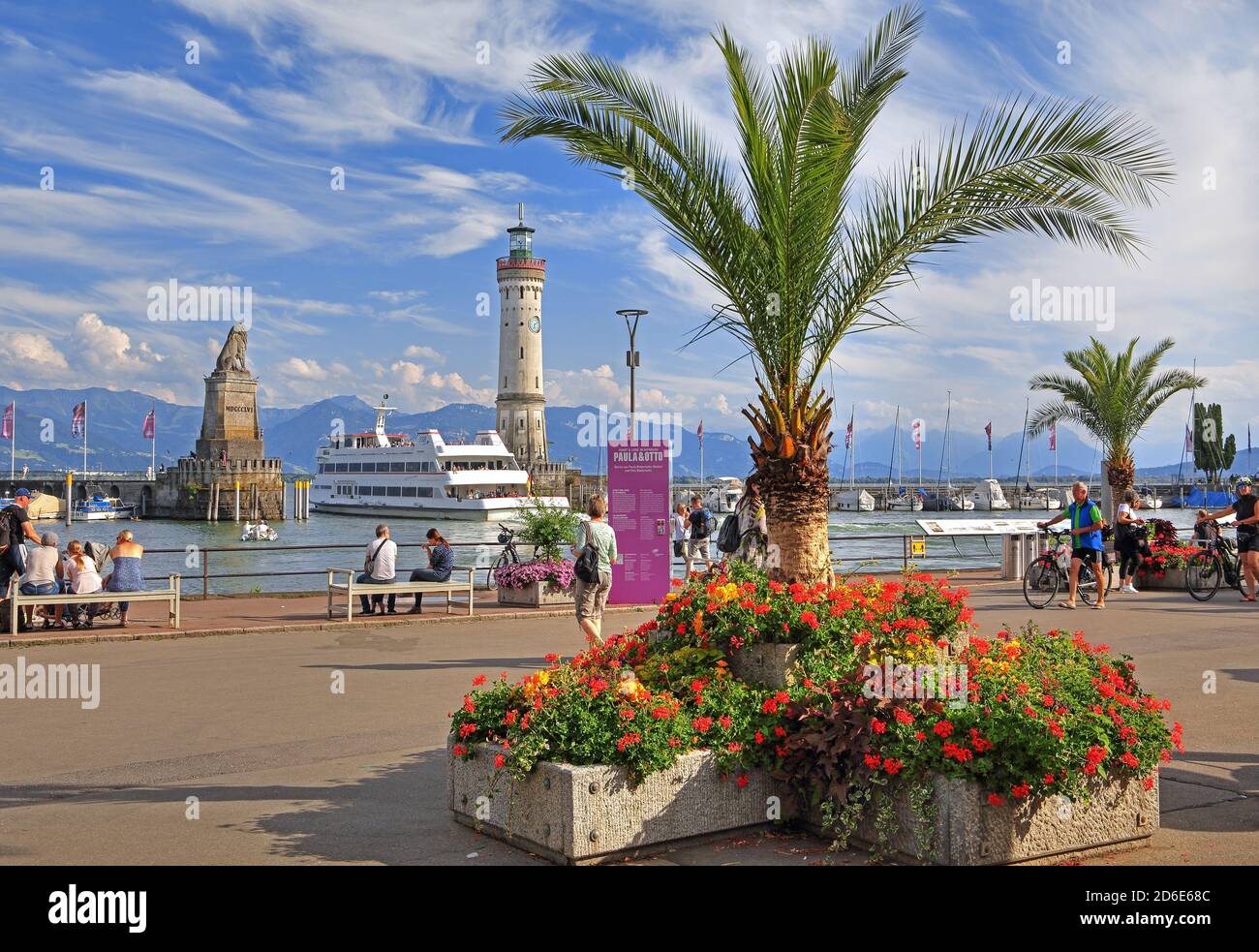 Hafenpromenade mit Blumenkästen und Palmen und Ausflugsboot in der ...