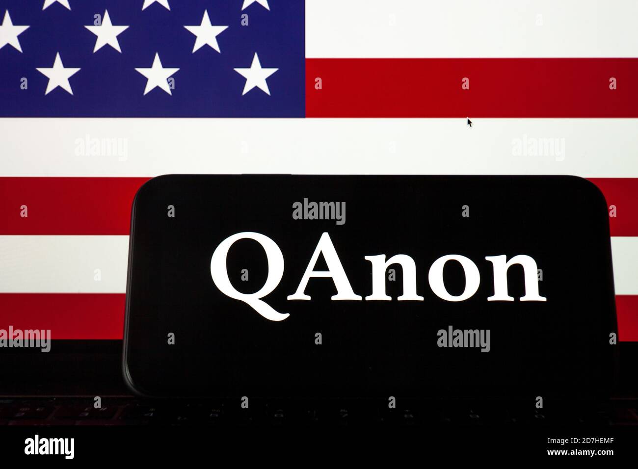 QAnon-Logo auf dem Smartphone, das auf der USA-Flagge platziert ist ...